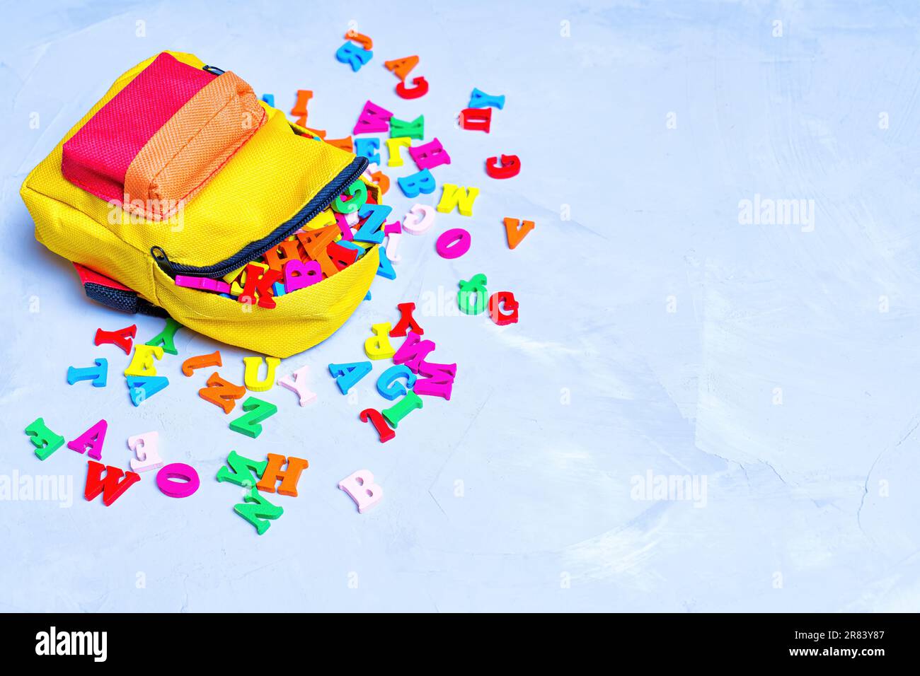 Tiny yellow and red backpack filled with wooden alphabet letters, with ...