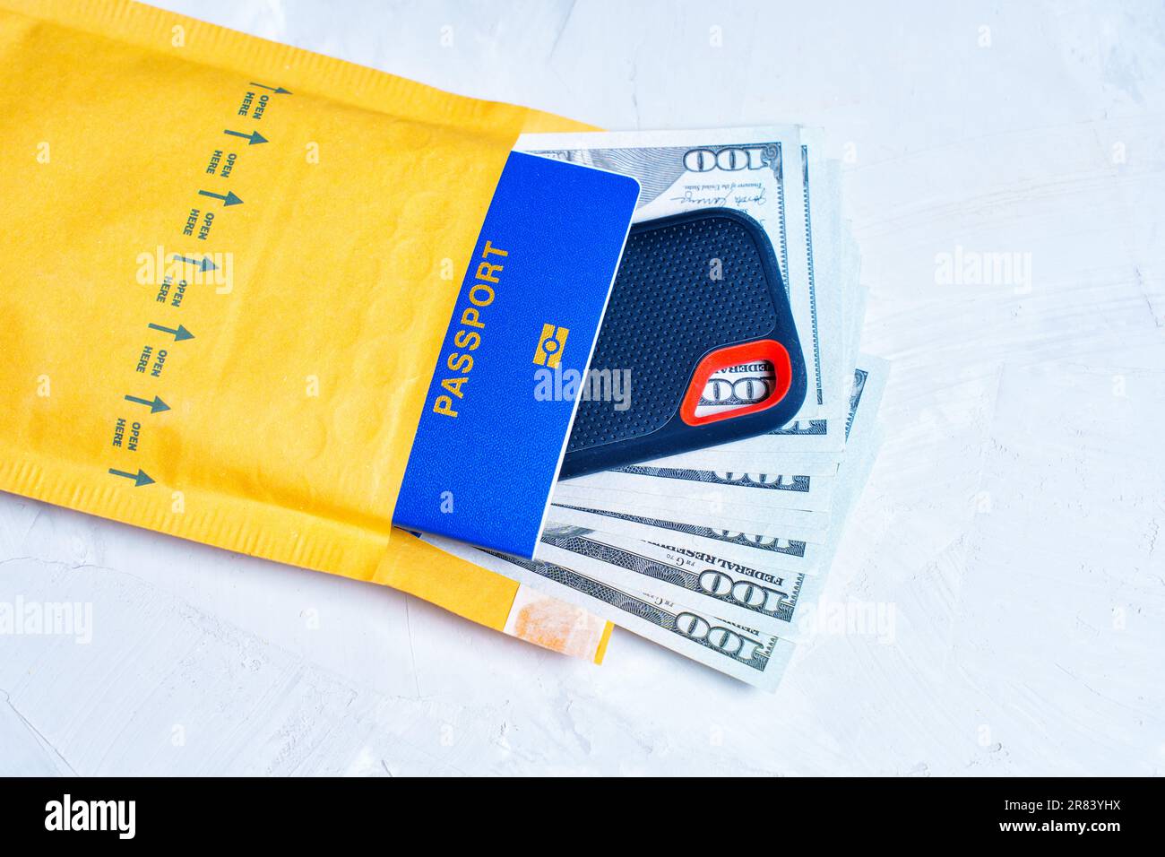 Padded yellow envelope with a passport, pile of hundred dollar bills ...