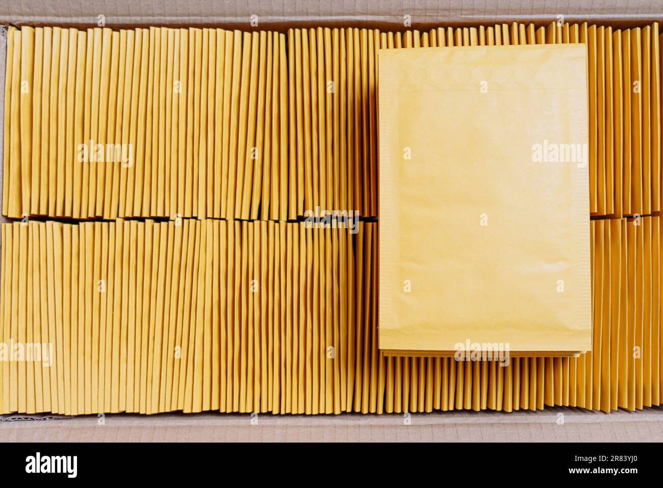 An open cardboard box filled with freshly printed yellow mail envelopes ...