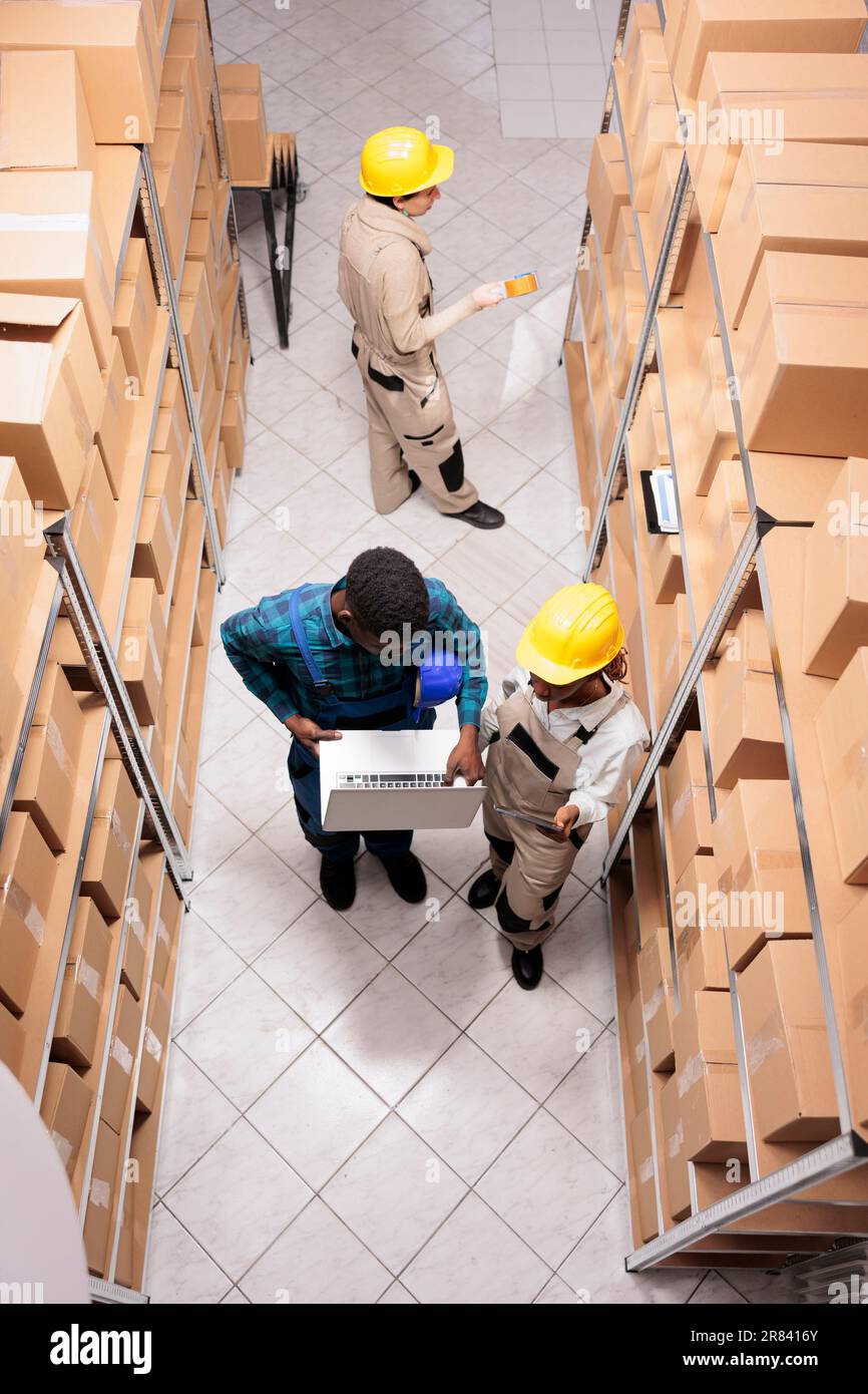 Storage room employees checking parcel delivery invoice on laptop ...