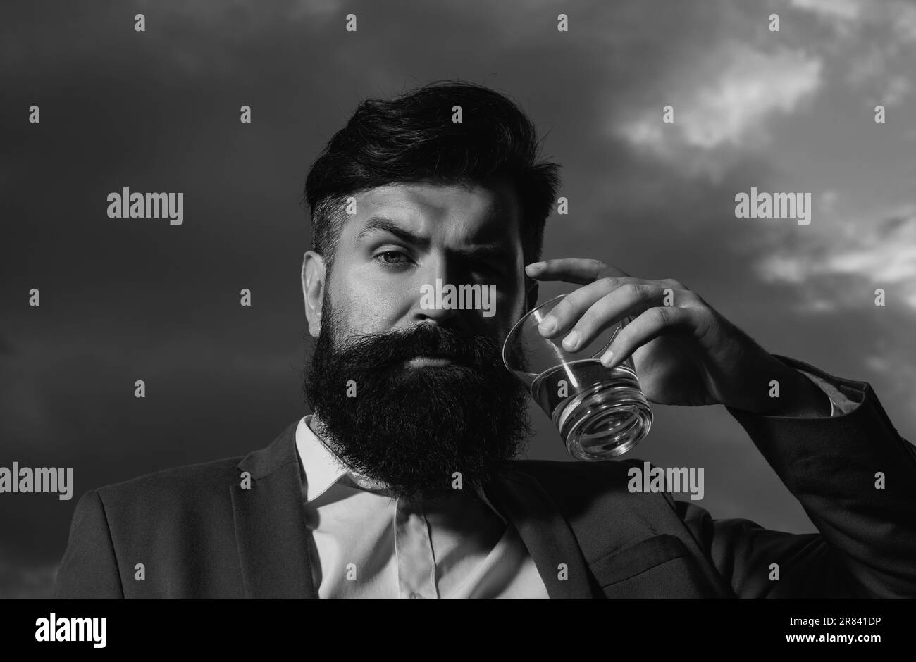 Handsome bearded man looking tired and upset drinking whiskey alone ...