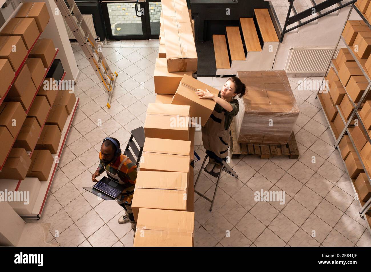 Aerial view of diverse team working with cardboard boxes in warehouse ...