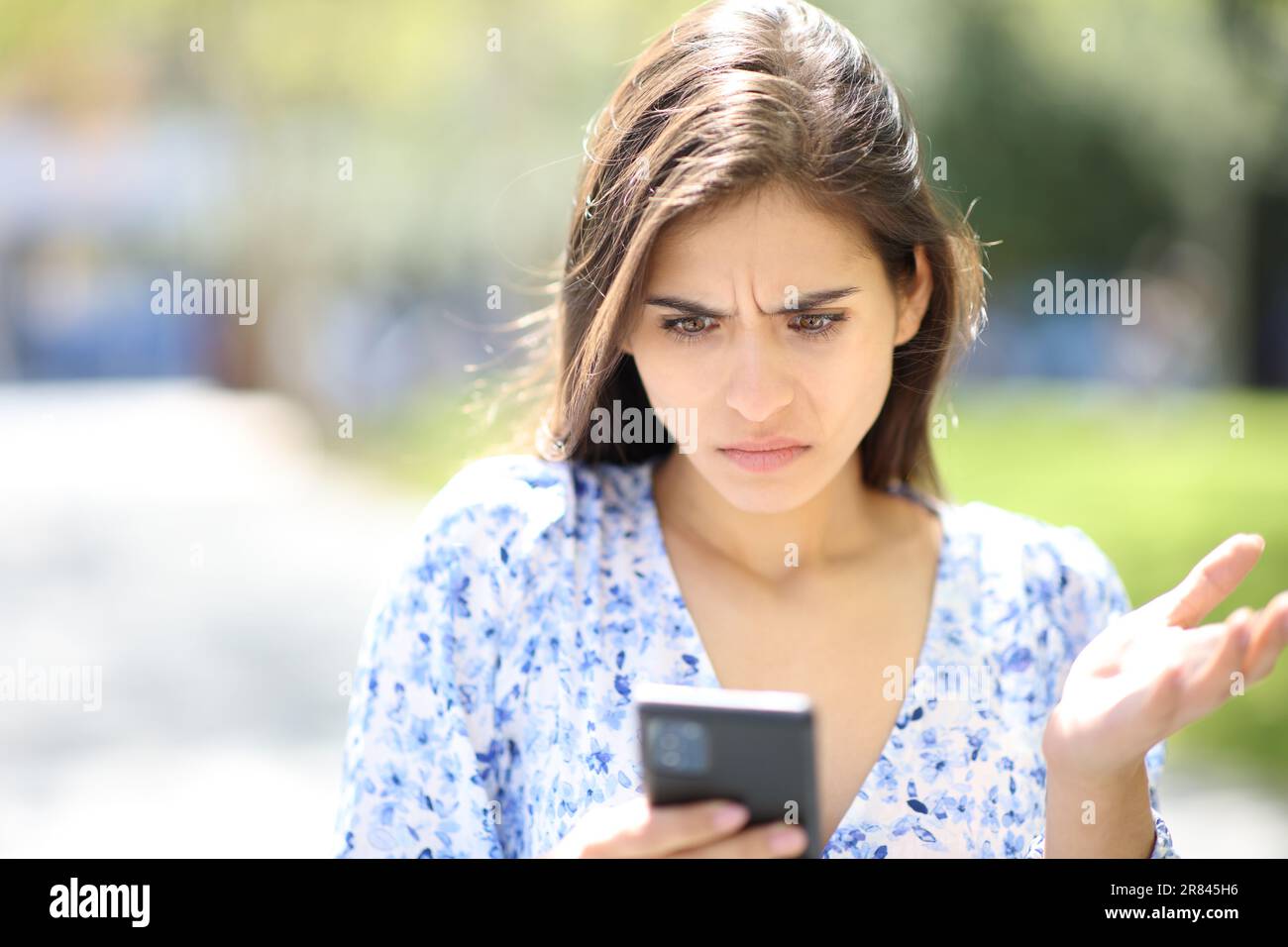 Upset woman checking phone content in the street Stock Photo - Alamy