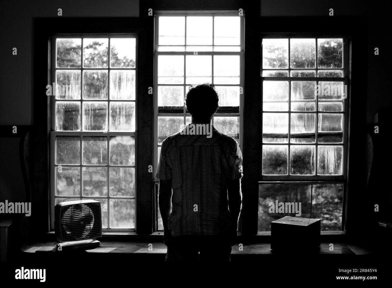 Man's silhouette in front of cabin windows Stock Photo - Alamy