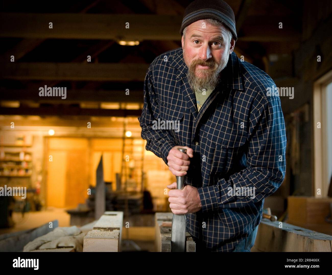 Taking a break from finishing a mortise joint, a timber framer glances ...