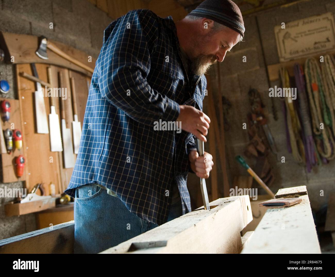 A timber framer uses a mortise chisel to clean out a mortise joint in ...
