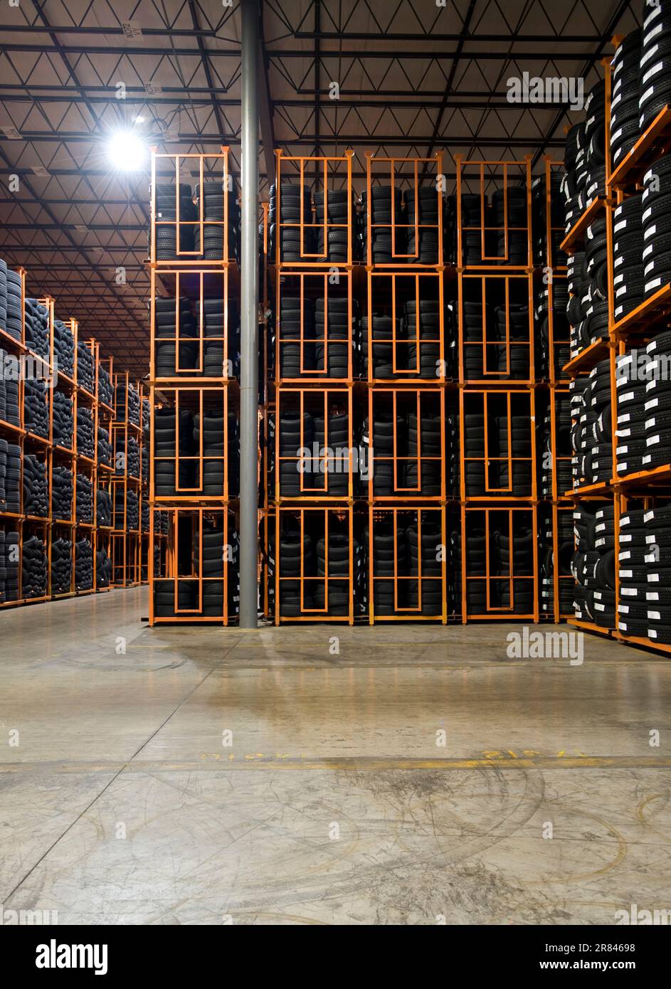 Tires for trucks and cars are stored in orange racks in a Warehouse ...