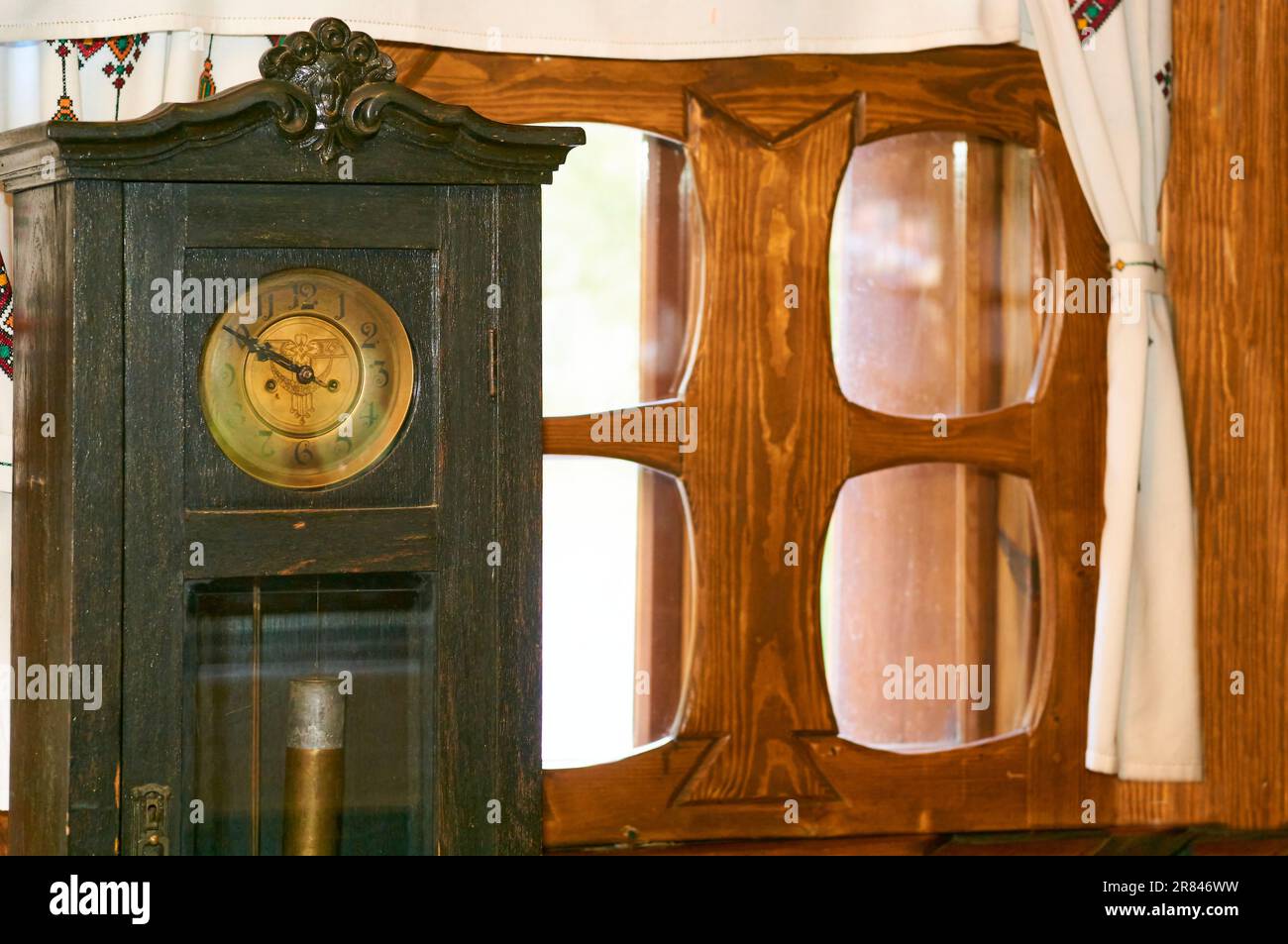 Vintage clock in a black wooden case by the window with a wooden frame ...