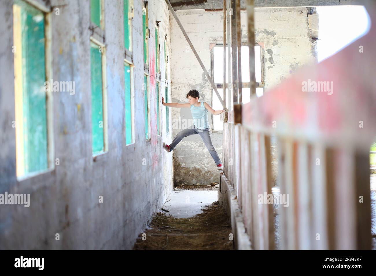 Boy Alone Hops Along Stalls in Abandoned Barn Stock Photo - Alamy
