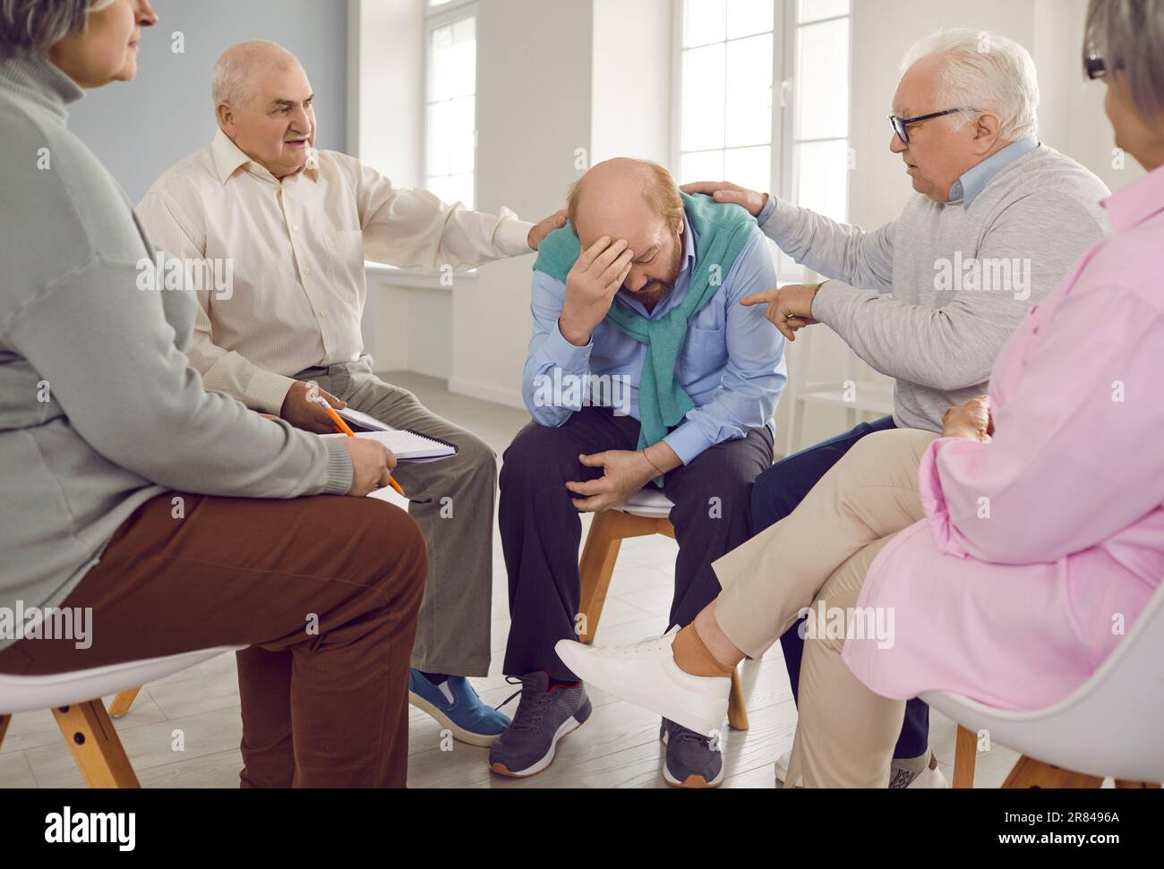 Group of friendly seniors people supporting elderly man on a therapy ...