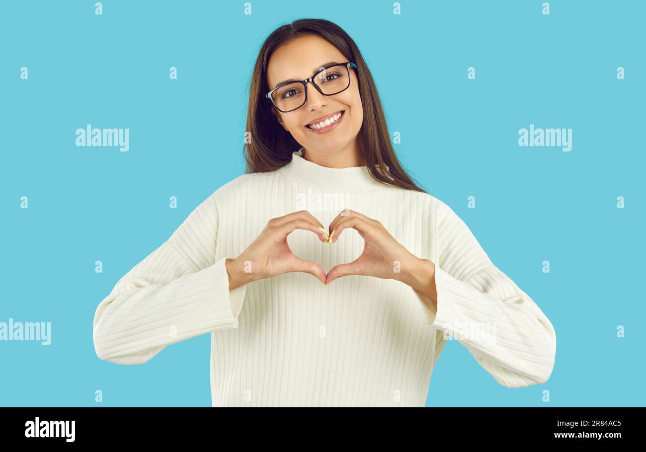 Portrait of beautiful friendly woman who shows loving gesture and expresses her sympathy to you ...