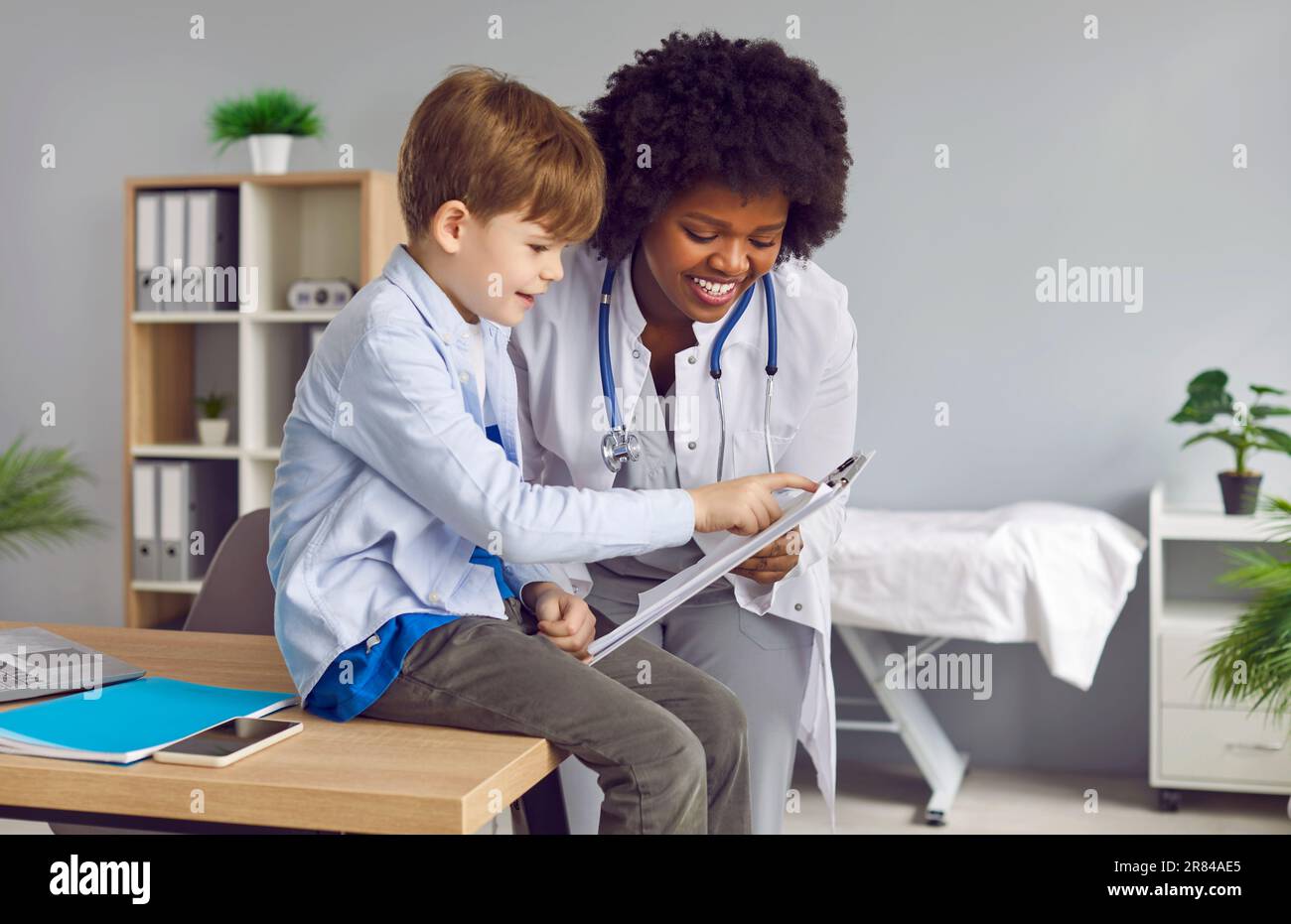 Happy African American woman pediatrician and a child look at something ...