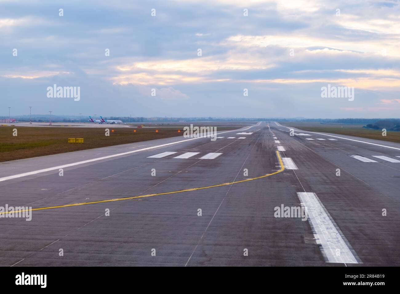 A long, straight runway stretches into the distance at the airport ...