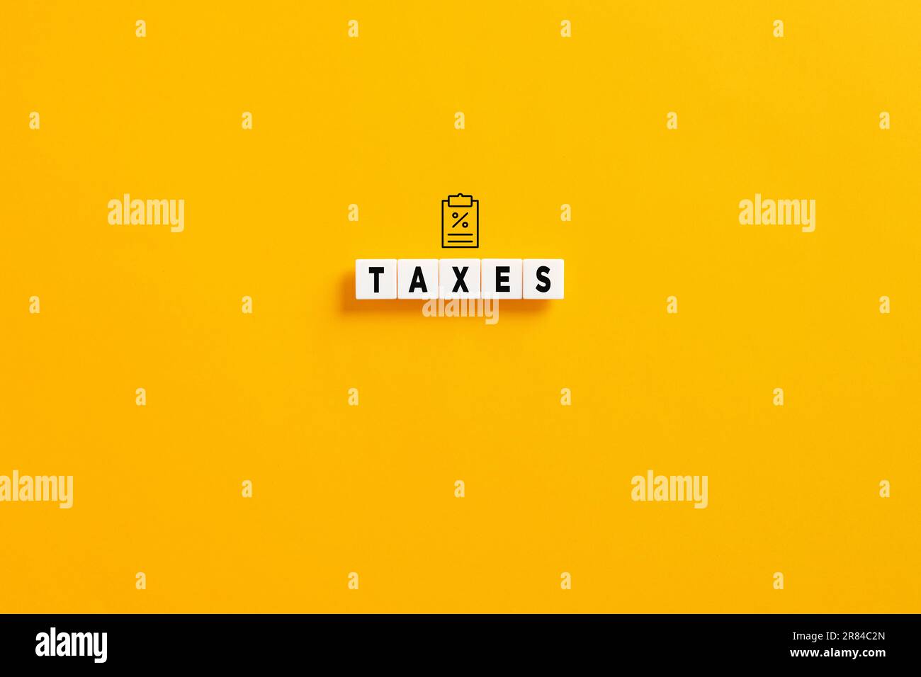 White letter blocks on yellow background with the word taxes. Tax ...