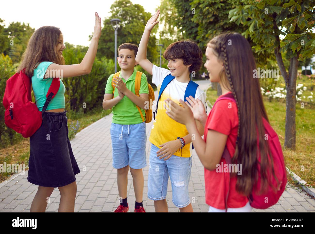 Happy little children with backpacks saying goodbye after school stand ...