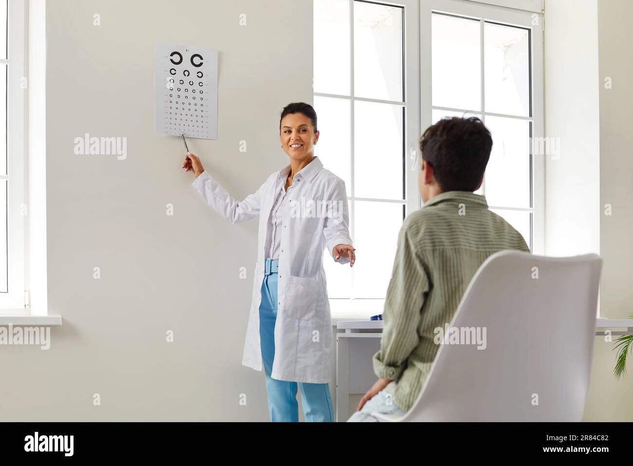 Ophthalmologist working with little child, doing eye exam and pointing ...