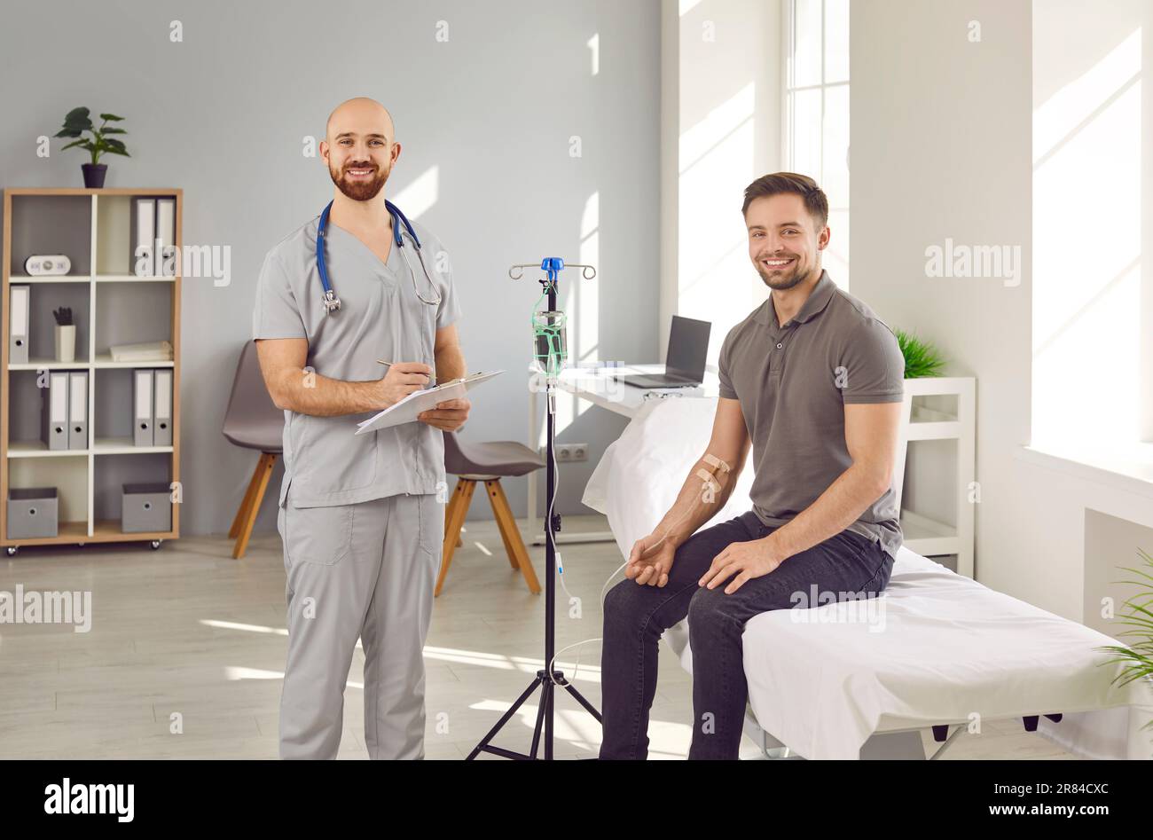 Portrait of happy patient getting intravenous vitamin therapy and nurse ...
