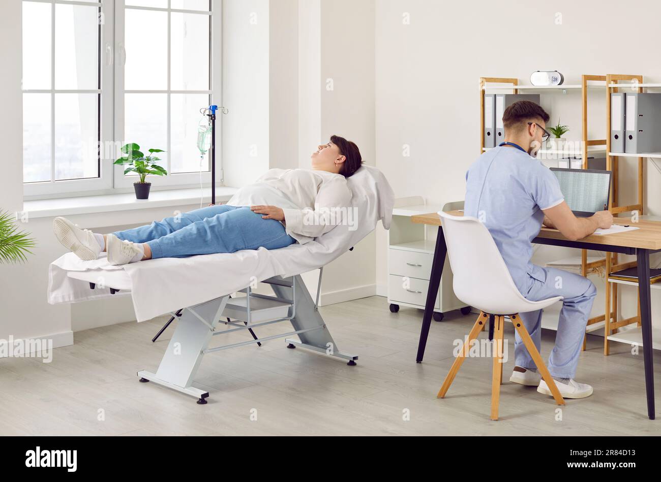 Patient on bed getting medical infusion through IV line while nurse is ...
