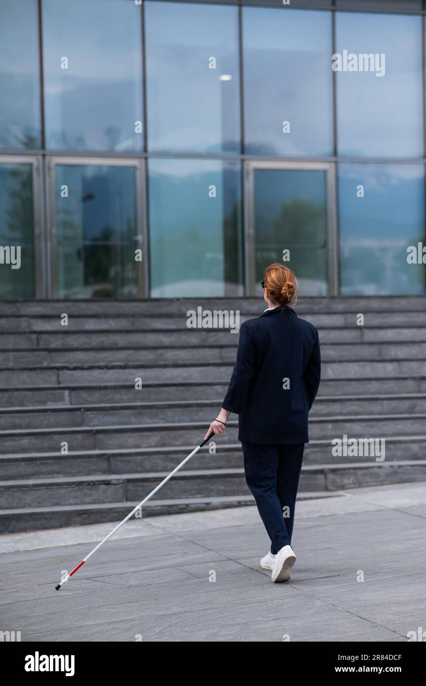 Blind businesswoman walking with tactile cane to business center Stock ...