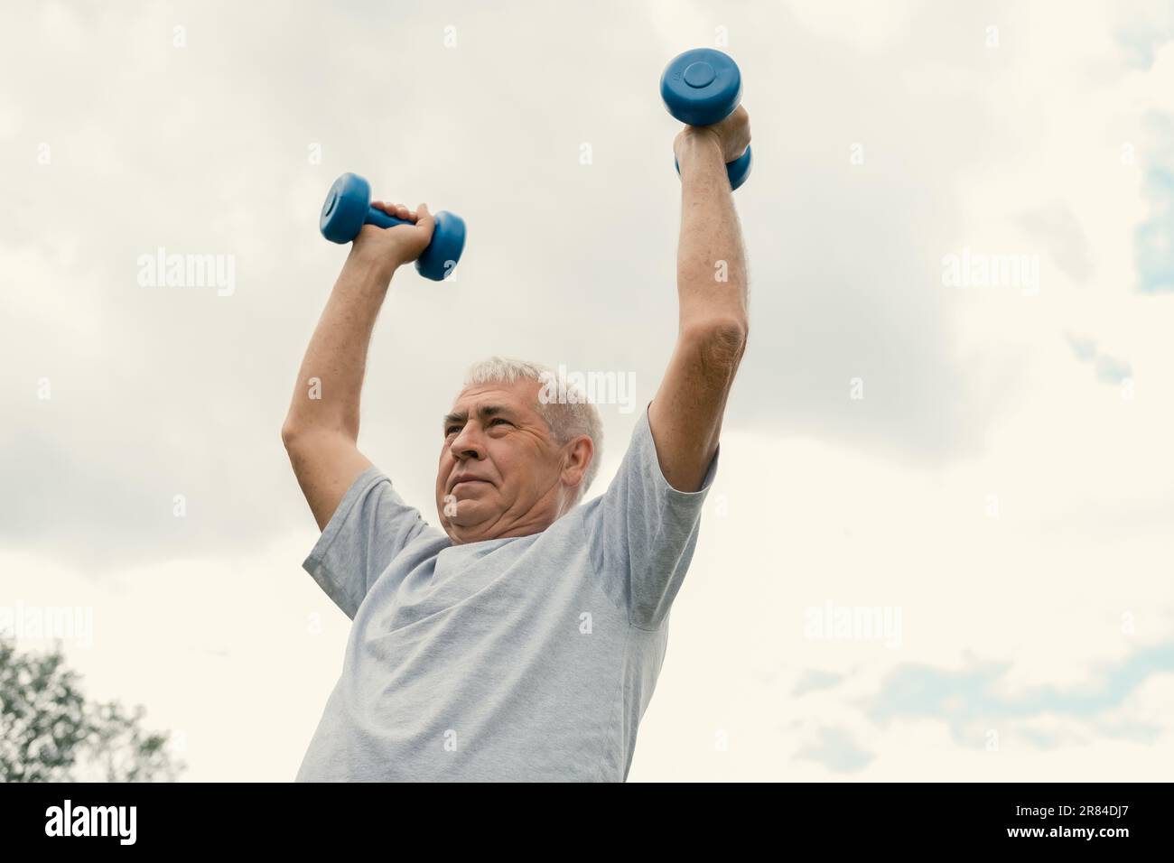 Senior man working out outdoors. Person lifting dumbbells. Old male ...