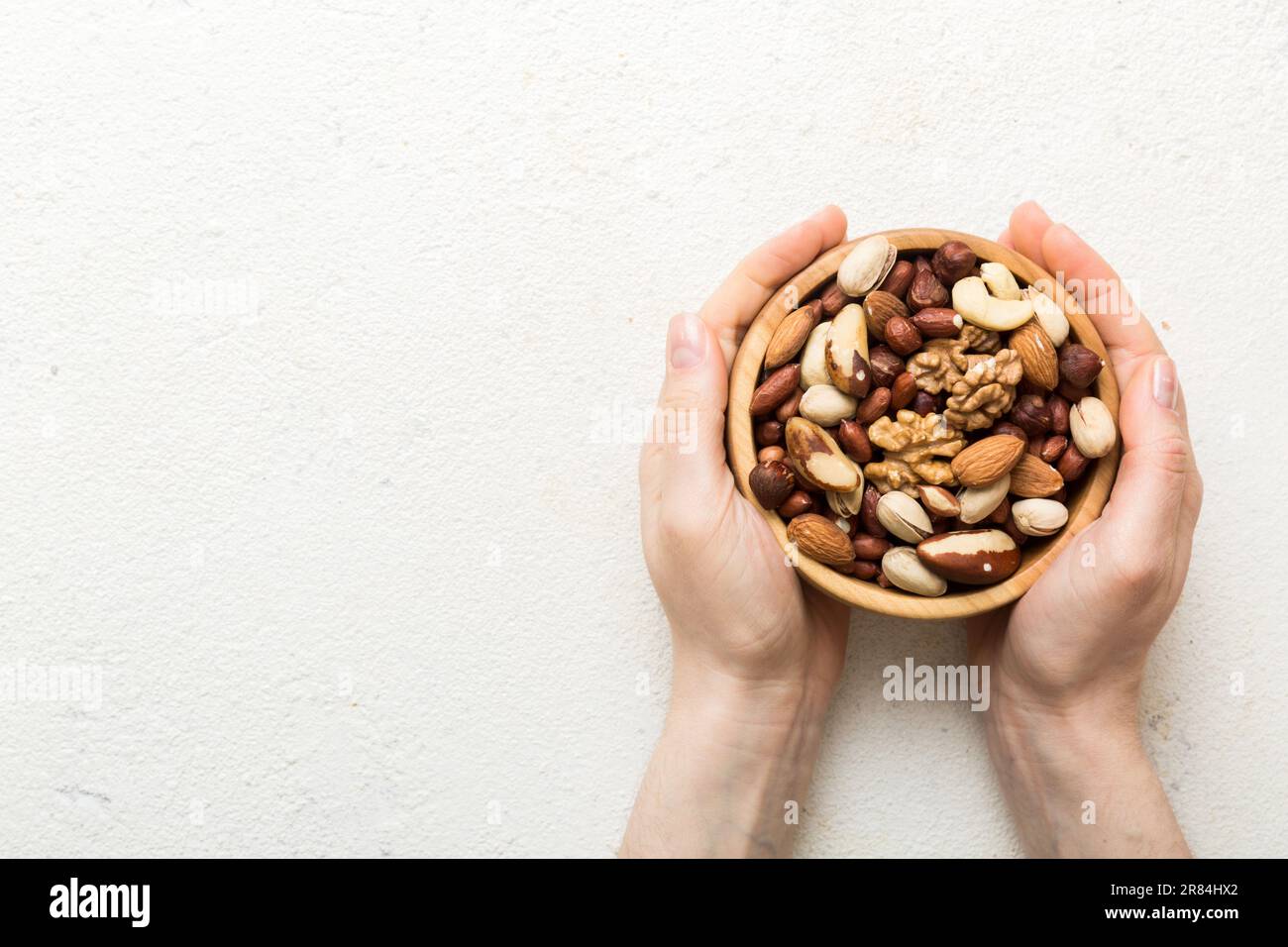 Woman hands holding a wooden bowl with mixed nuts Walnut, pistachios ...