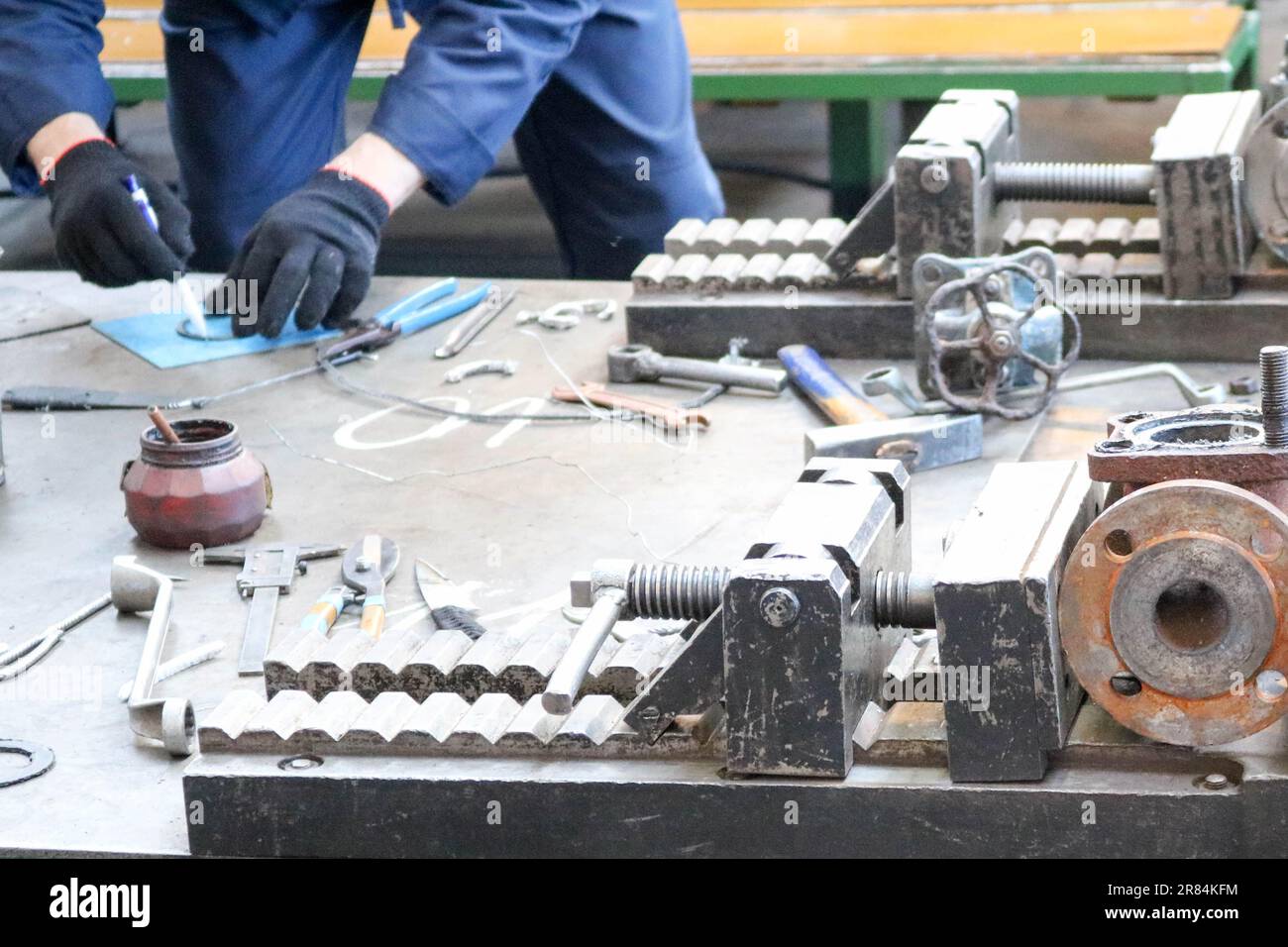 The worker works on a table with a metalwork tool in the factory ...