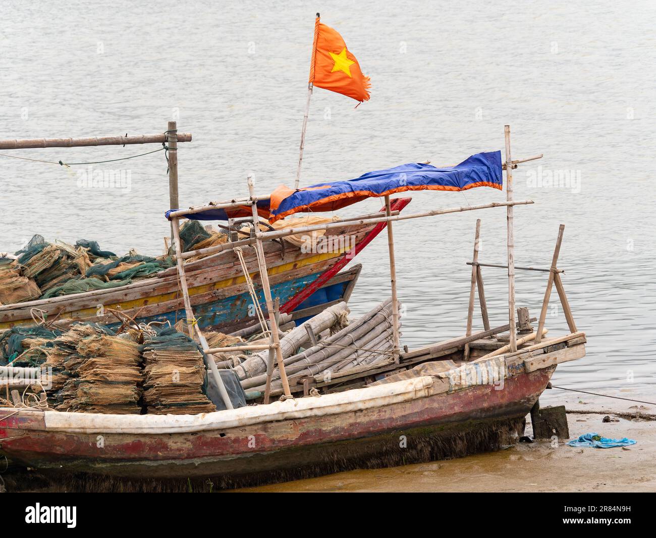 Old, wooden fishing boats with fishing nets and a Vietnamese flag ...