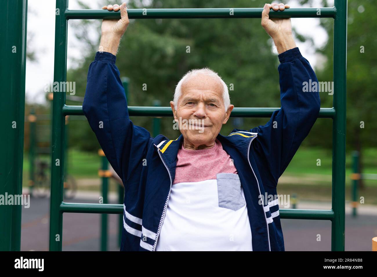 Active grandpa pulls up on horizontal bar on sports ground Stock Photo ...