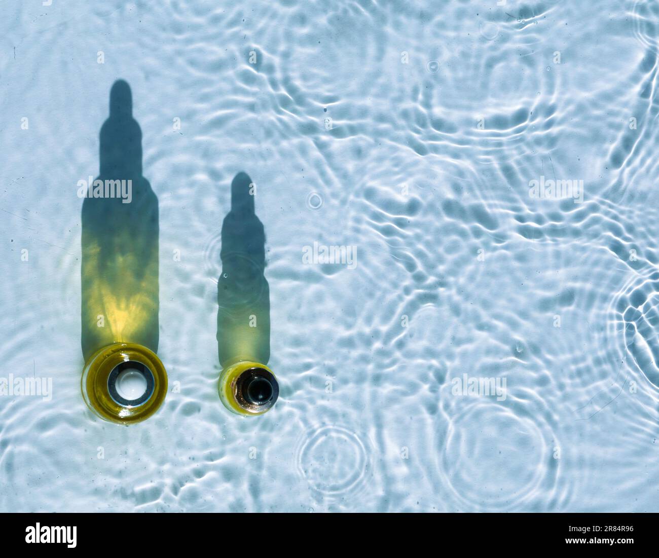 Yellow cosmetic bottles on the water surface. Blank label for branding ...