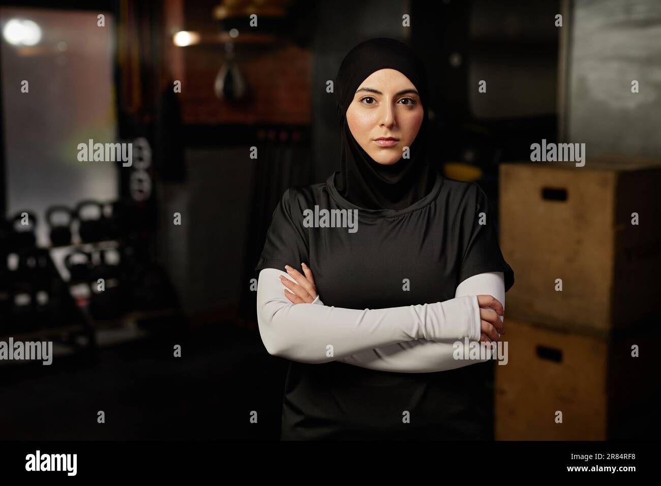 Young Muslim female fitness instructor in hijab looking at camera while ...