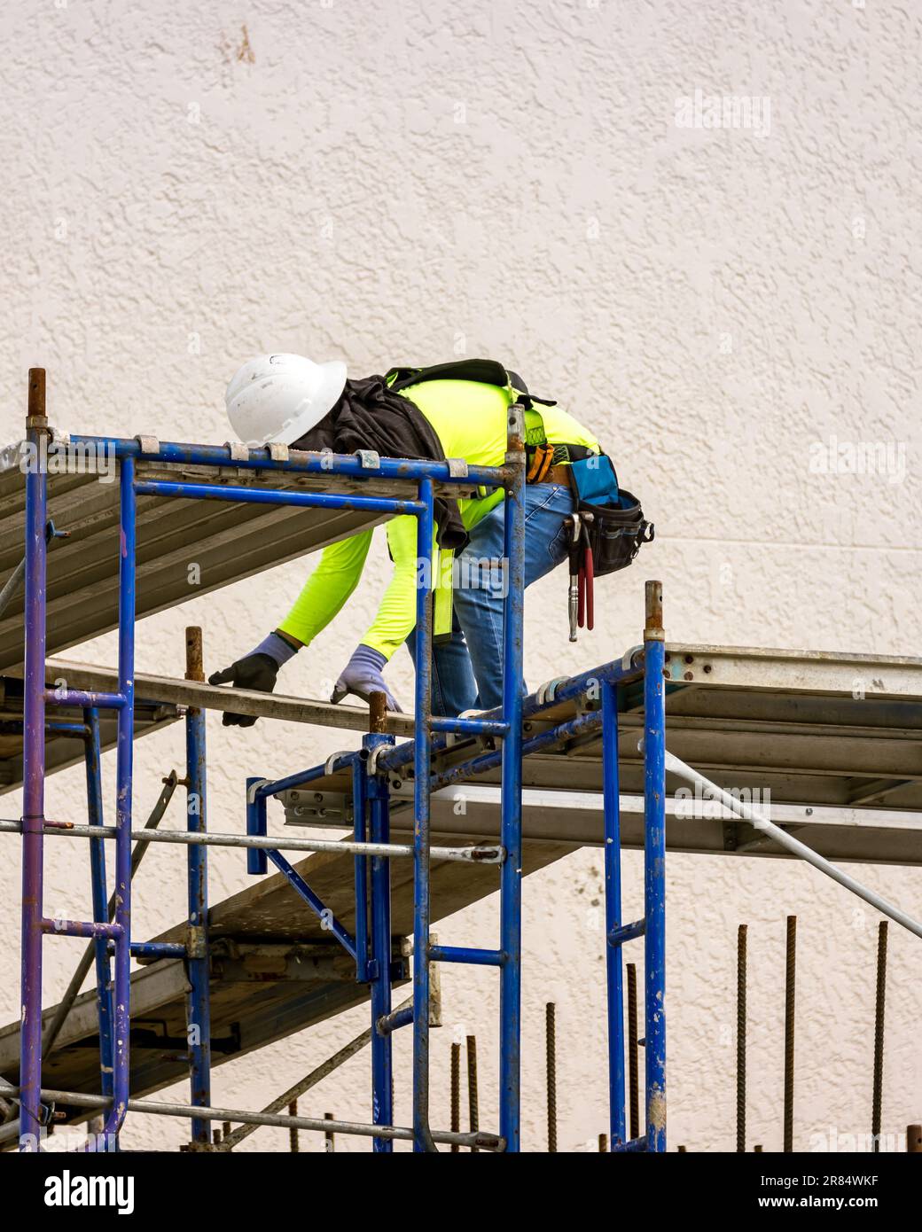 A construction worker with face mask installing scaffolding for ...