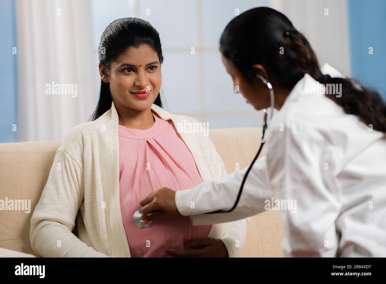 Shoulder shot of Indian doctor examining baby movement of pregnant ...