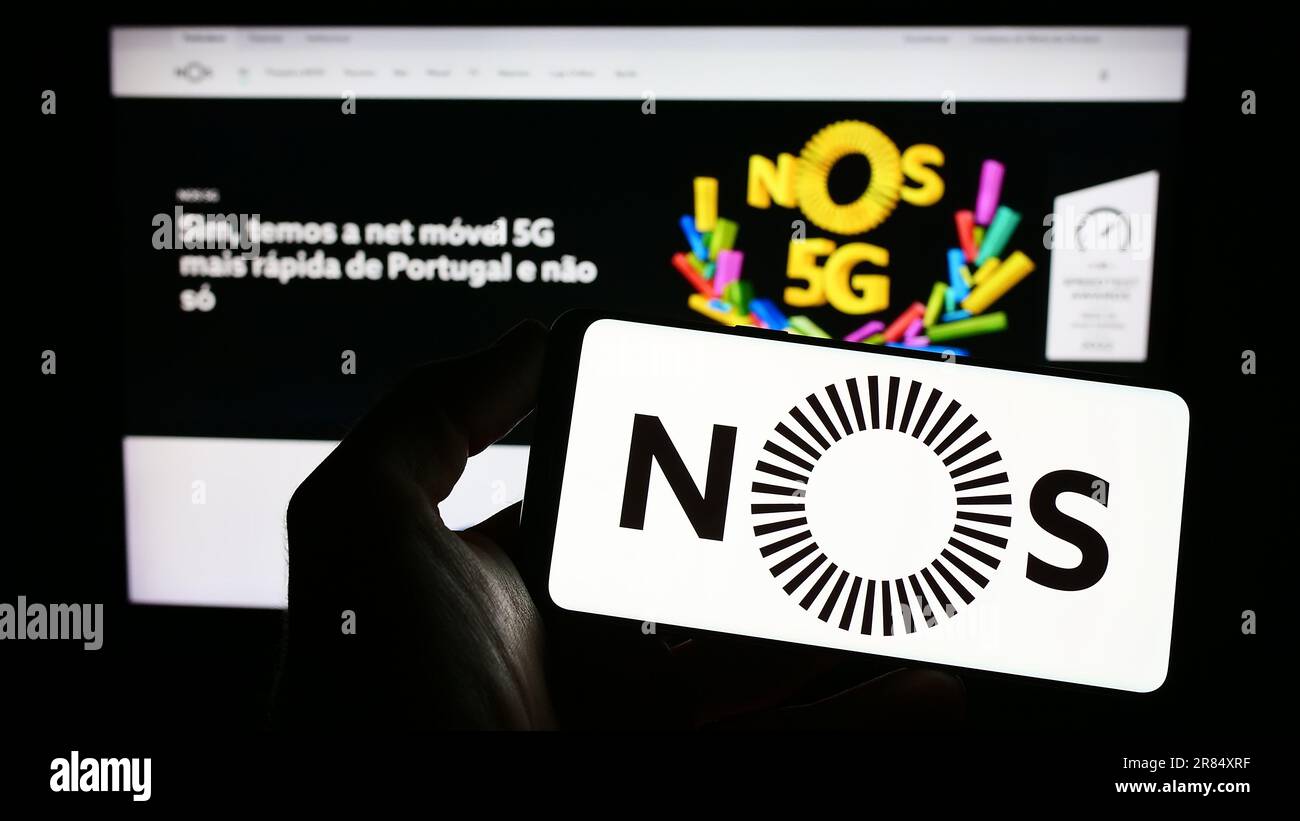 Person holding smartphone with logo of telecommunications company NOS ...