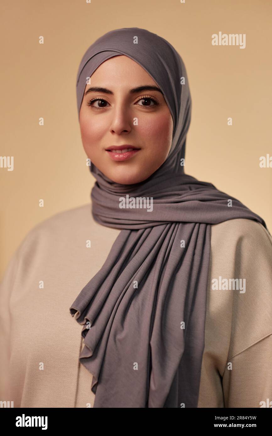 Young beautiful Muslim woman in grey headscarf and beige pullover ...