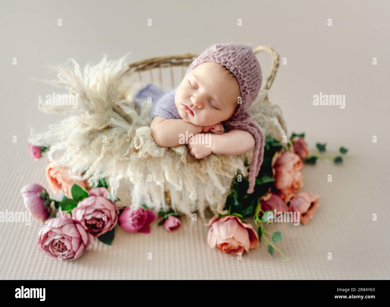 Newborn baby girl sleeping on fur and peony flowers. Cute infant child ...