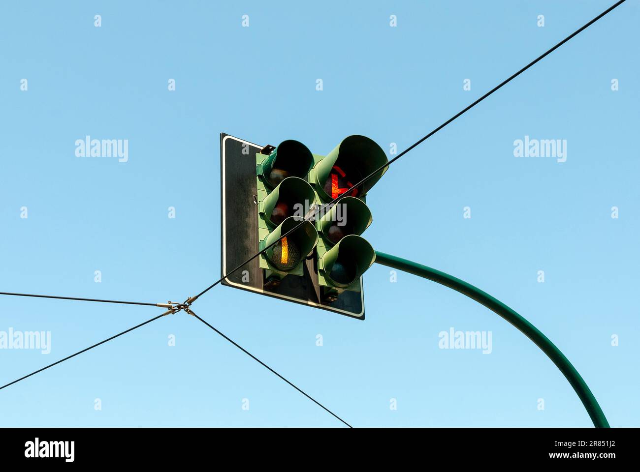 Traffic lights suspended above a road junction, blue sky background ...