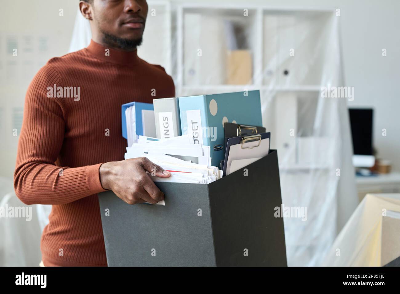 African American man carrying box with folders during movement in new ...