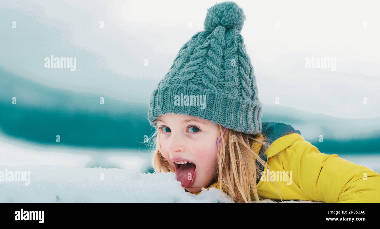 Winter girl eating snow outdoor. Kids cold and flu concept. Kid lick ...
