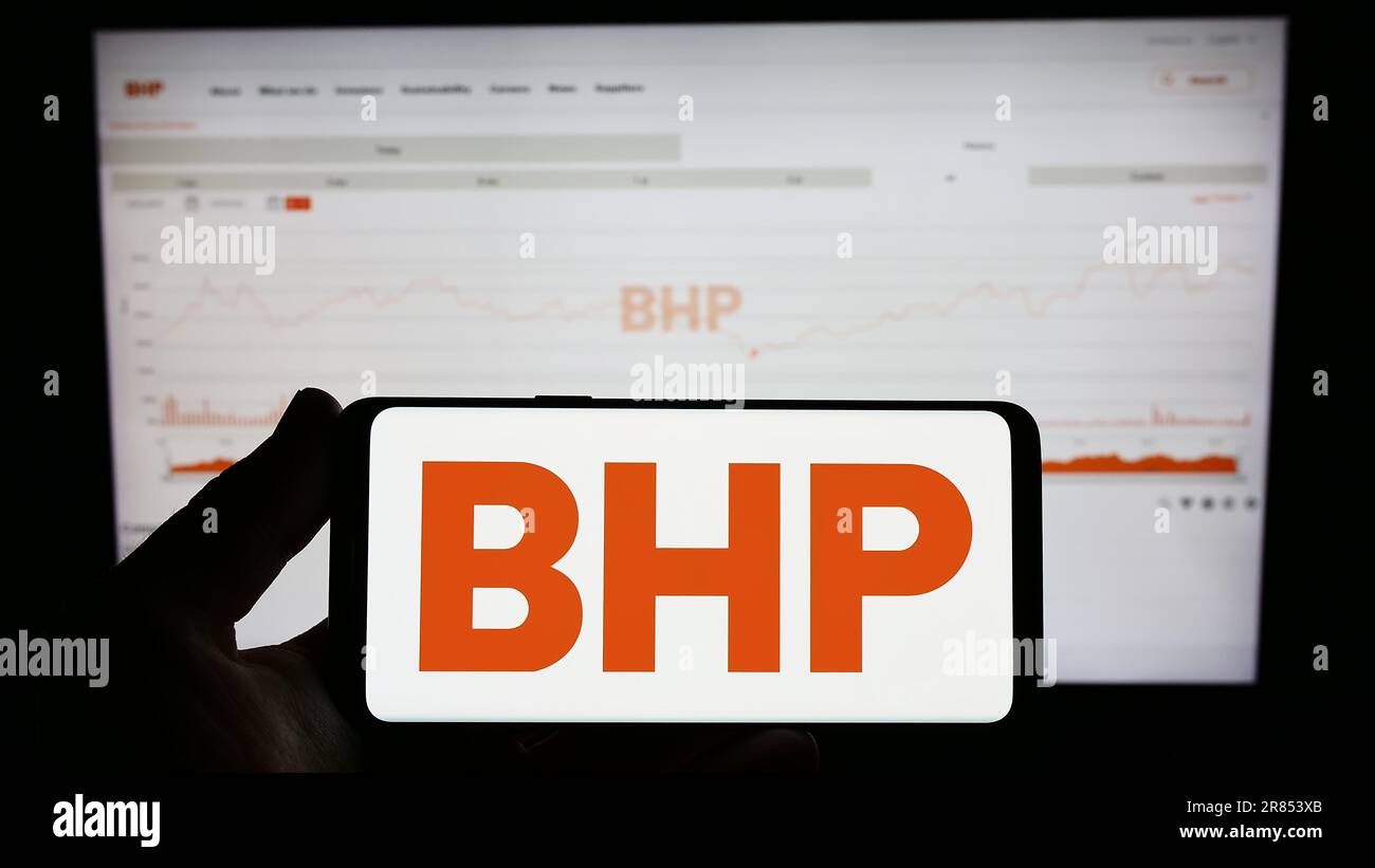 Person holding mobile phone with logo of Australian mining company BHP ...