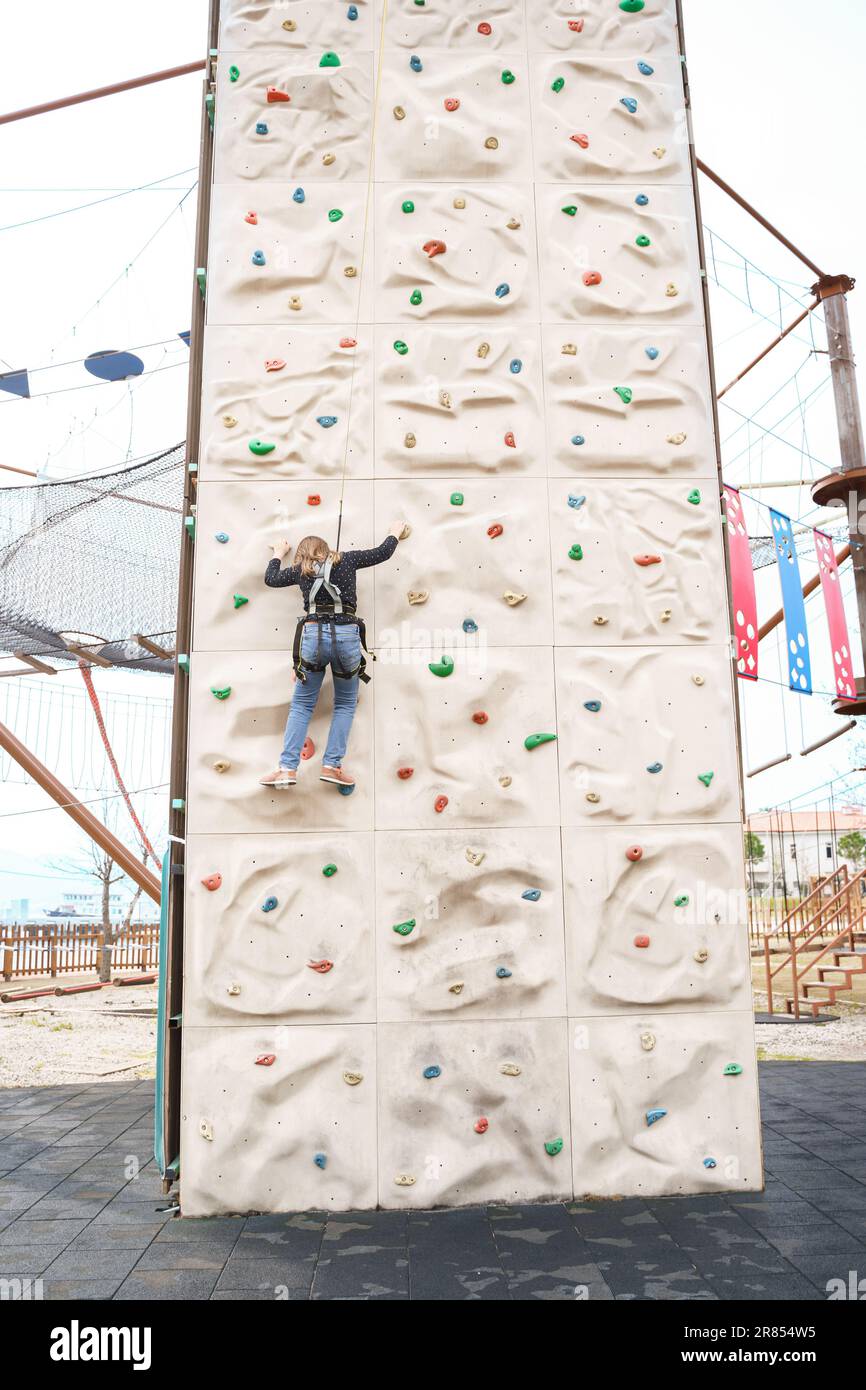 Teenage teen girl grabbing artificial high climbing wall with split ...