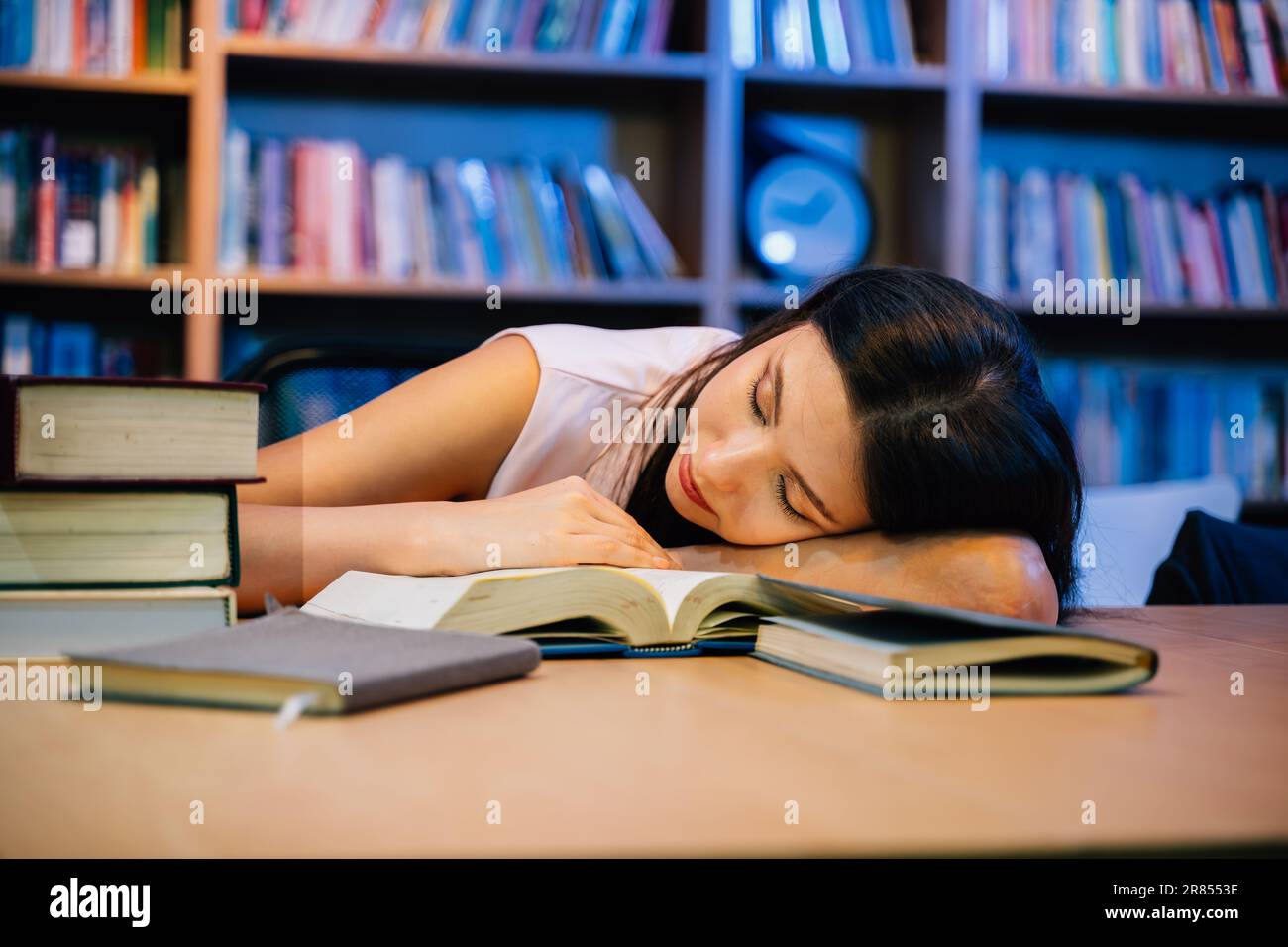 Young woman napping on table in library for education Stock Photo - Alamy