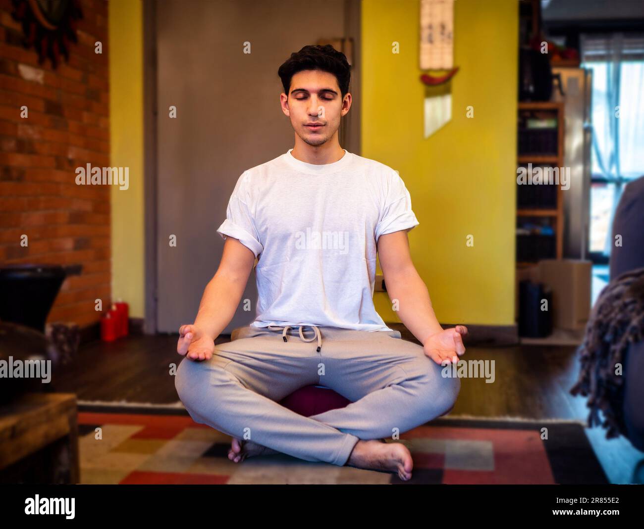 Young man meditating on the floor, sitting in the lotus position Stock ...