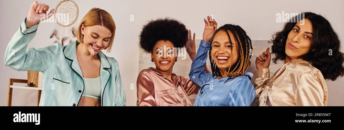 Positive multiethnic girlfriends in colorful pajama dancing and having ...
