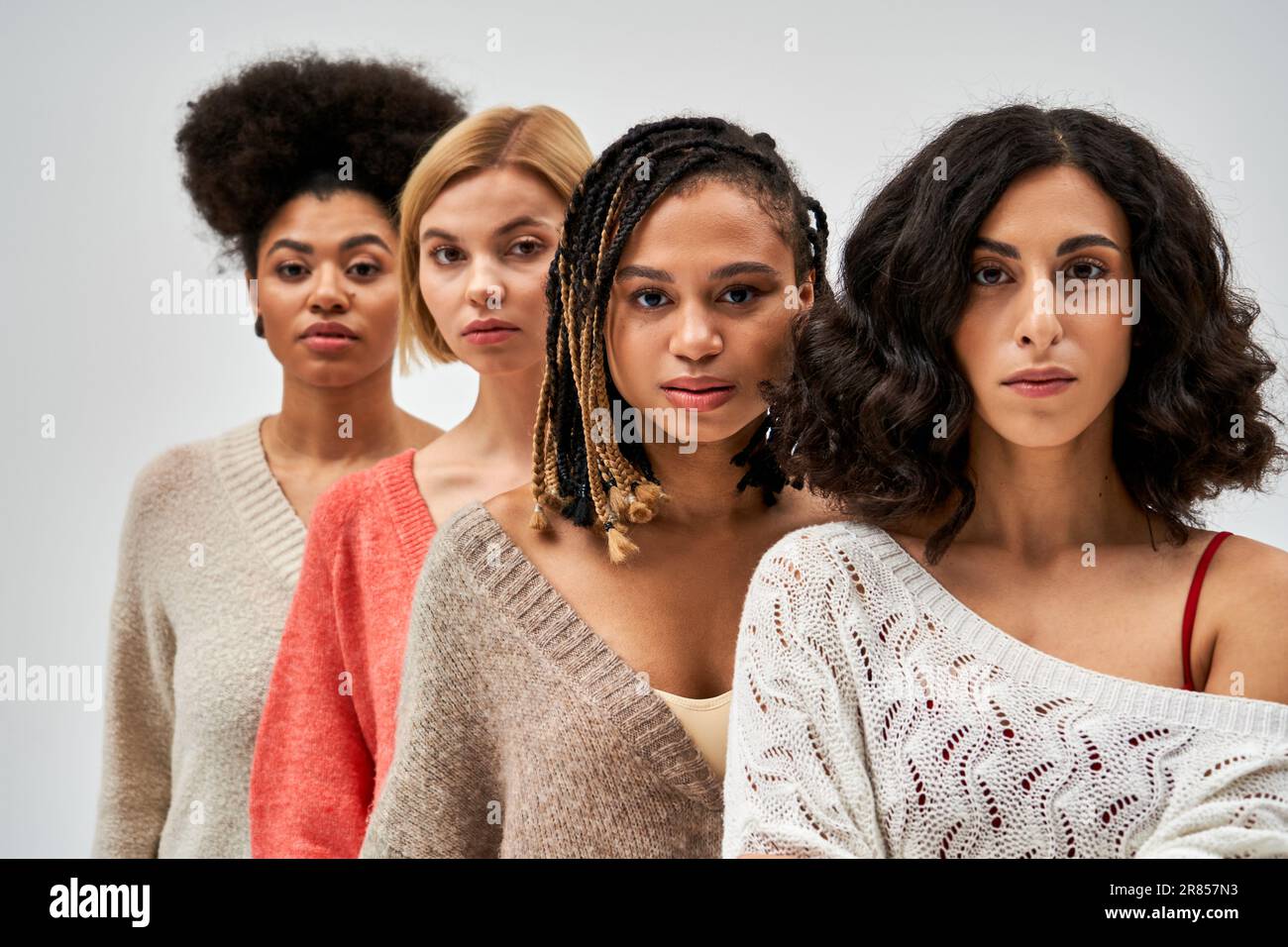Portrait of multiethnic women in stylish warm sweaters looking at ...