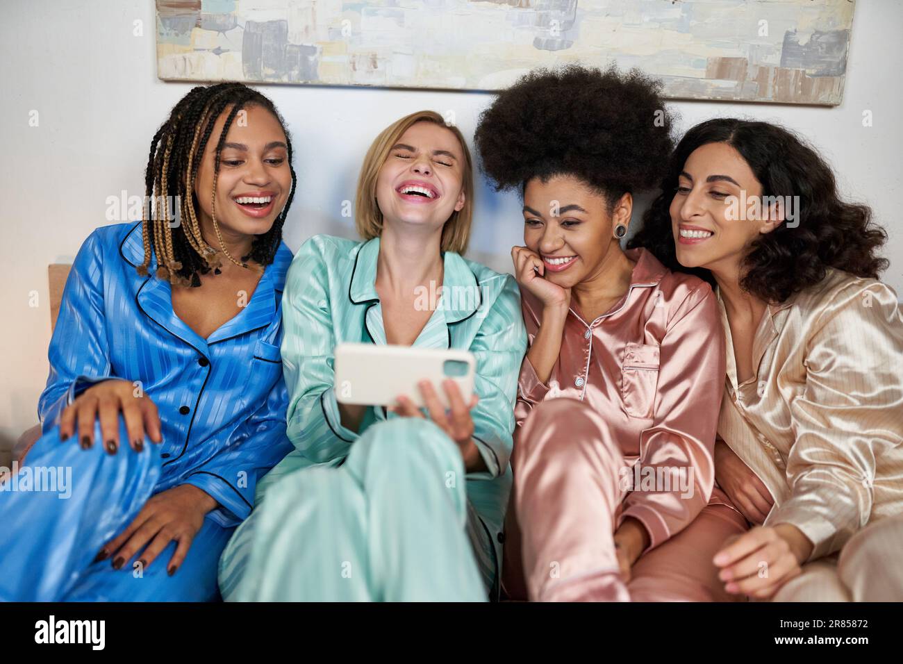 Young and laughing blonde woman holding blurred smartphone near ...