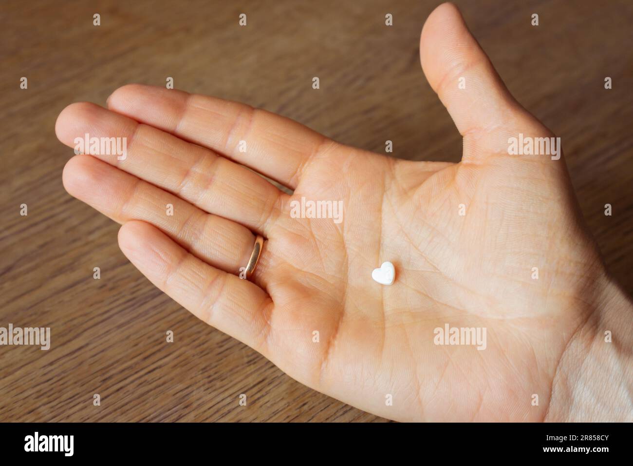 White pill on open palm hand. Heart shape pill in hand. Medical ...