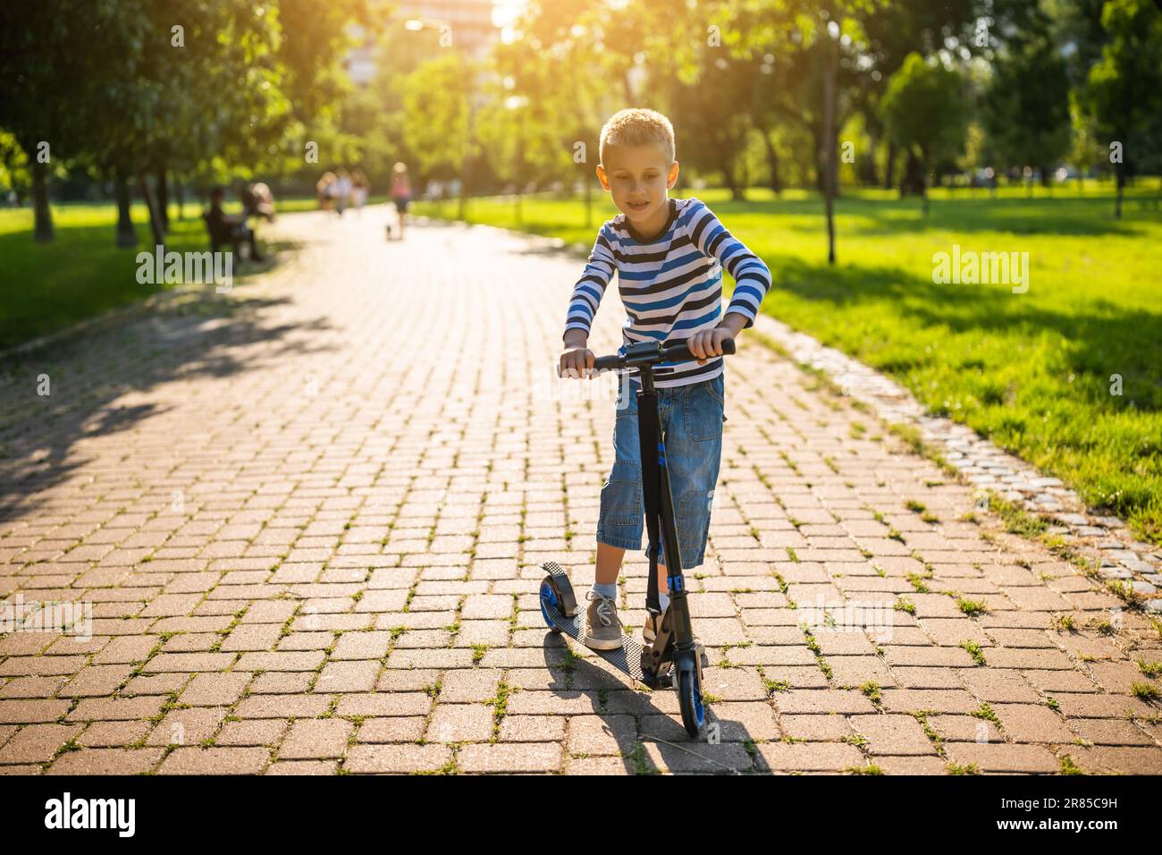 Boy riding scooter on sunny hi-res stock photography and images - Alamy