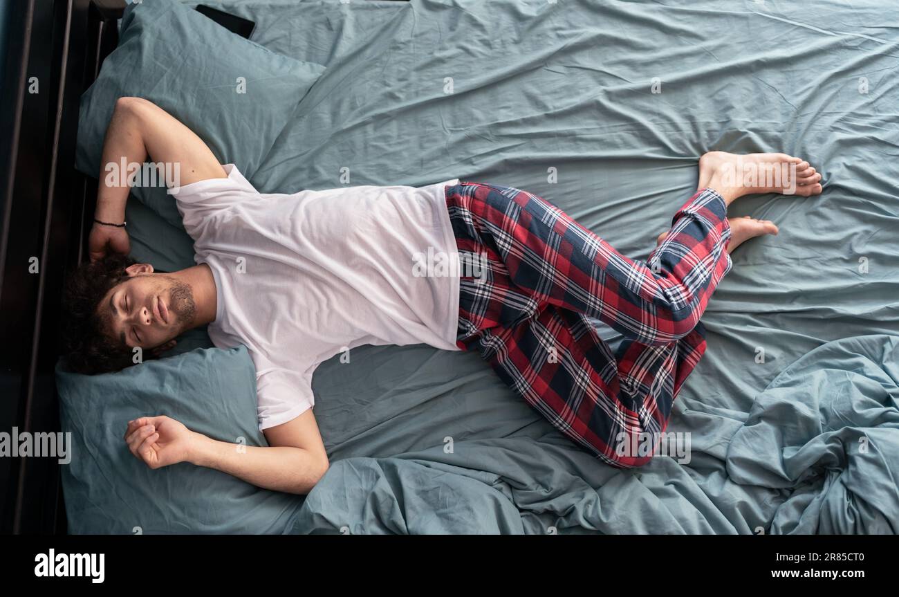 Top view of young arab guy in pajamas resting at home, sleeping on his ...