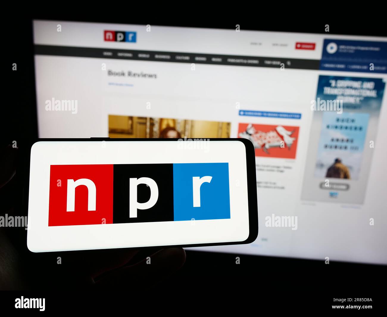 Person holding mobile phone with logo of media organization National ...