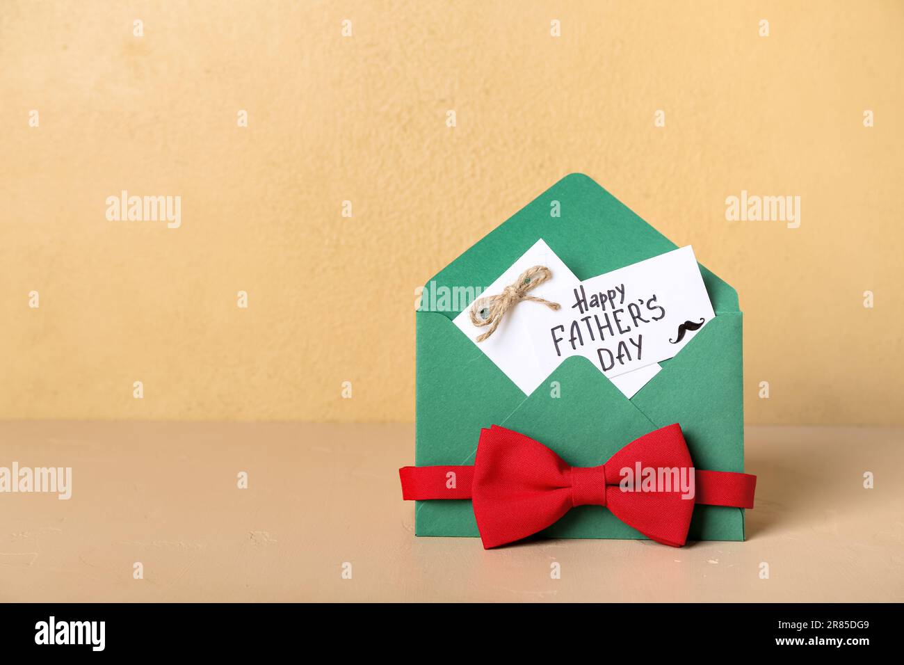 Envelope with text HAPPY FATHER'S DAY and bow tie on beige background ...
